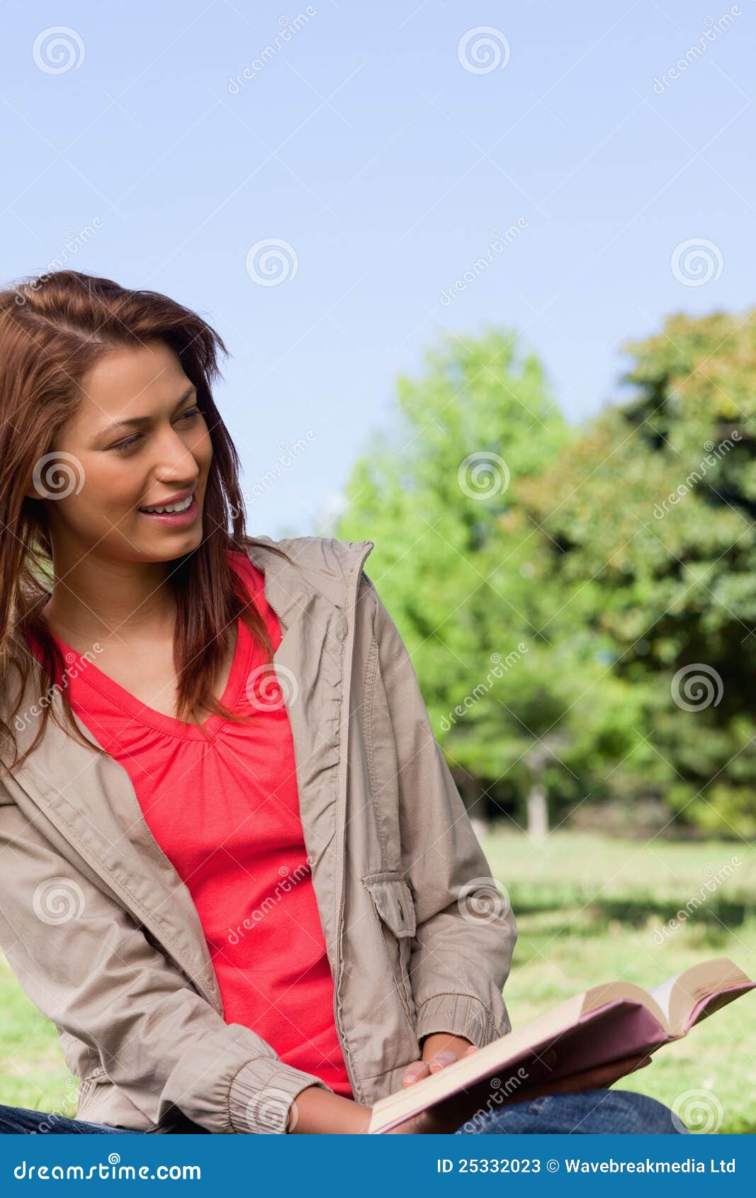 Woman Reading A Book While Sitting Down In A Bright Park Stock Image