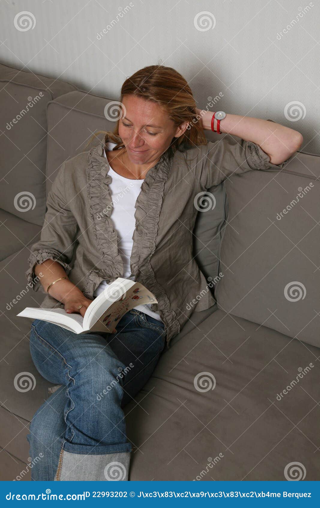 Woman reading book on sofa stock photo. Image of middle - 22993202