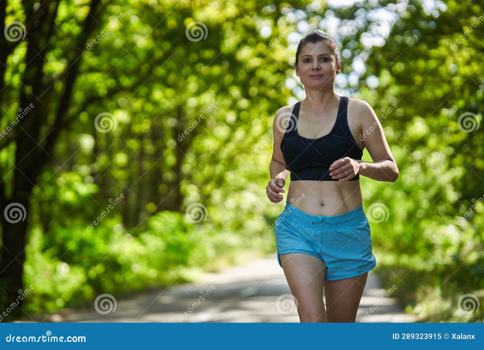 Woman Running through Forest on Asphalt Stock Image - Image of healthcare, runner: 289323915