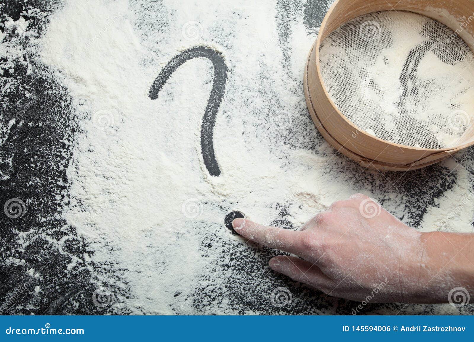 A Woman`s Hand Draws a Question Mark on Flour. Sieve for Flour and the ... A Woman`s Hand Draws a Question Mark on Flour. Sieve for Flour and the ...