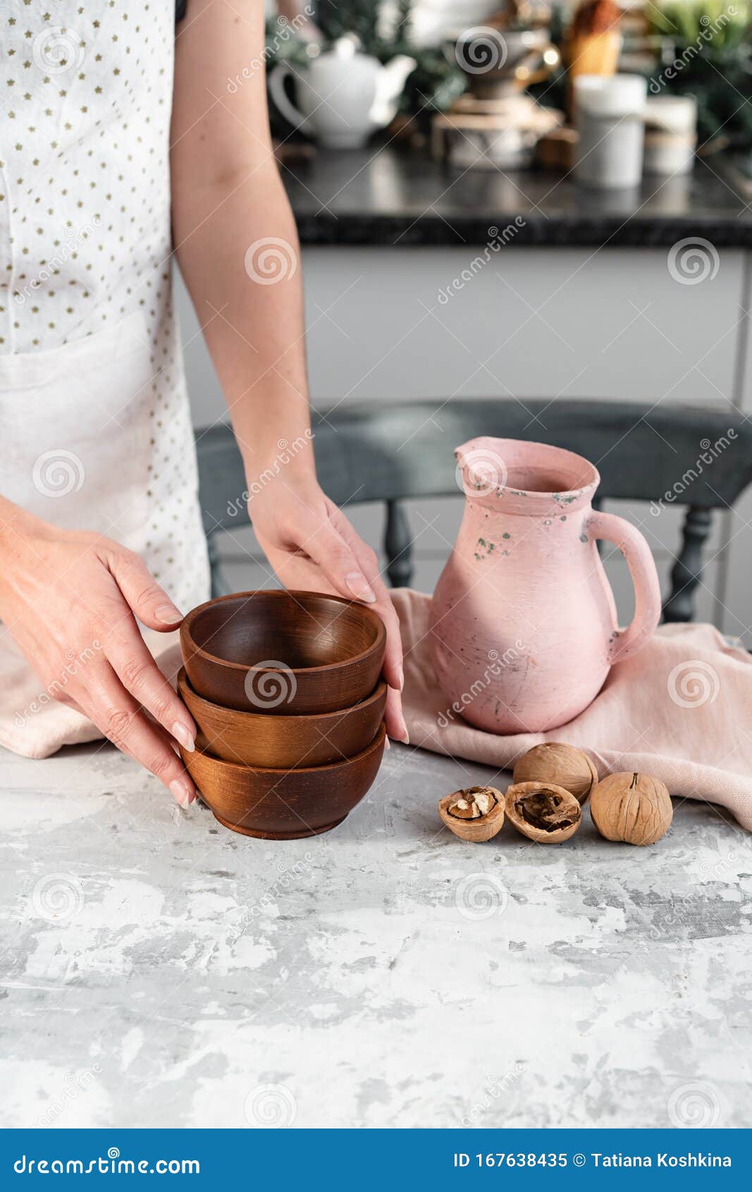 Woman`s Hands in an Apron Put on the Table with a Jug a Stack of Wooden ...