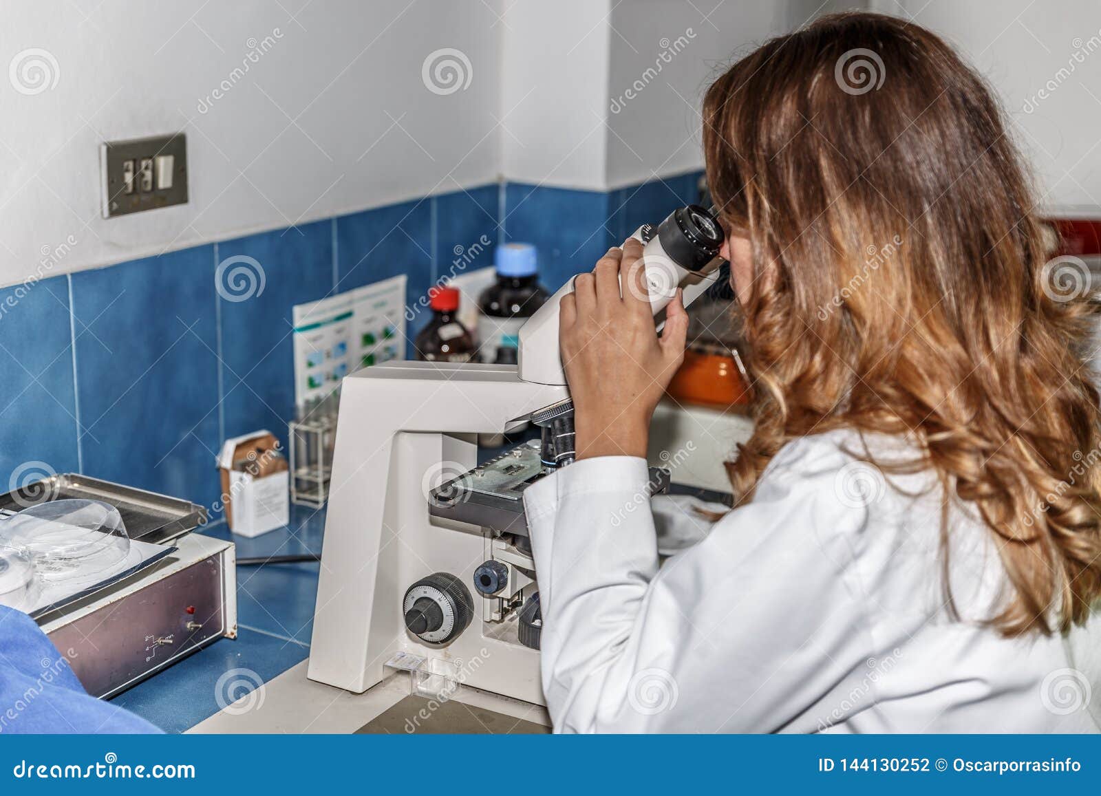 A Woman Scientist is Carefully Analyzing Samples with a Microscope ...