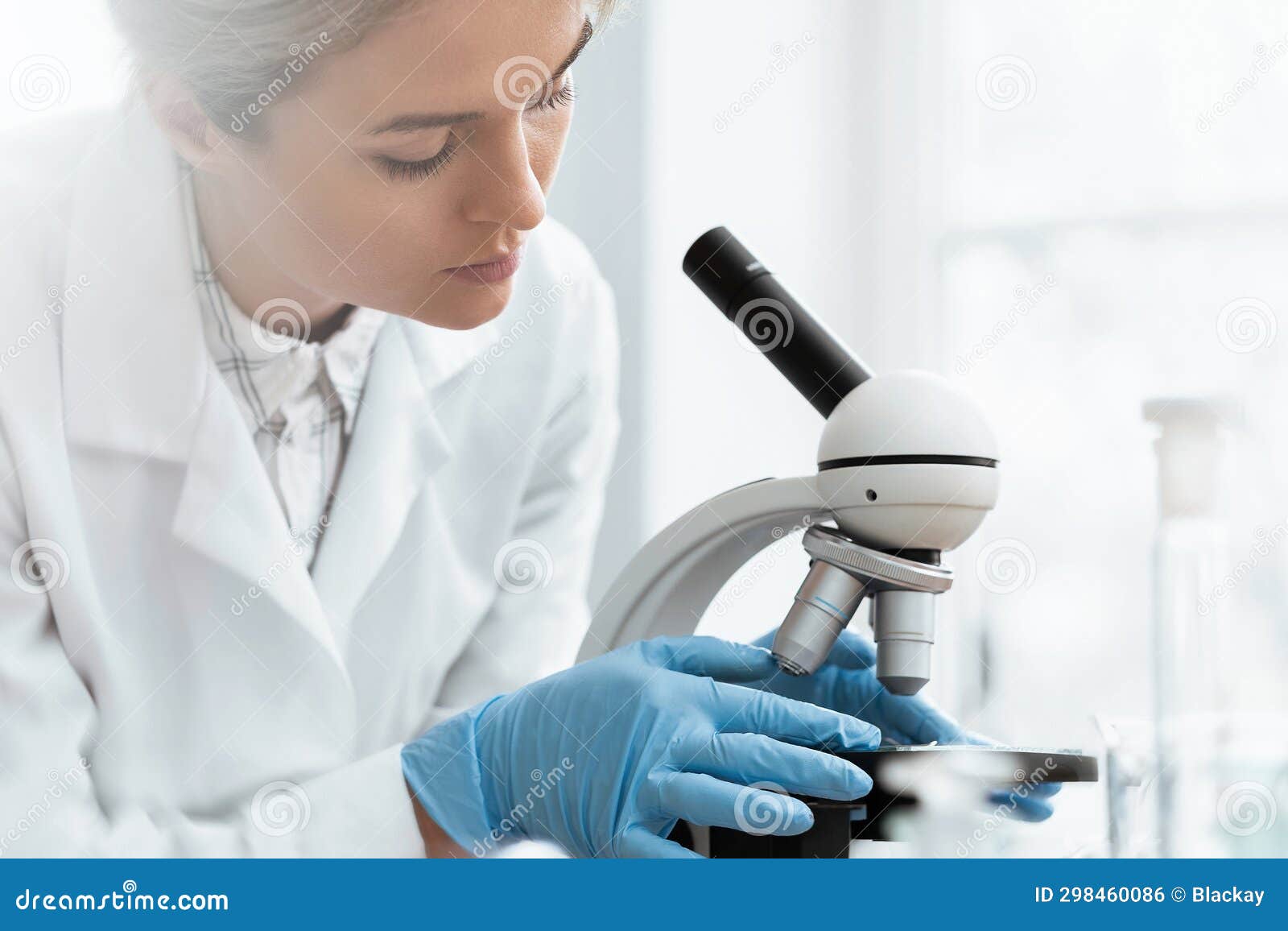 Woman Scientist is Using Microscope in a Laboratory during Research ...