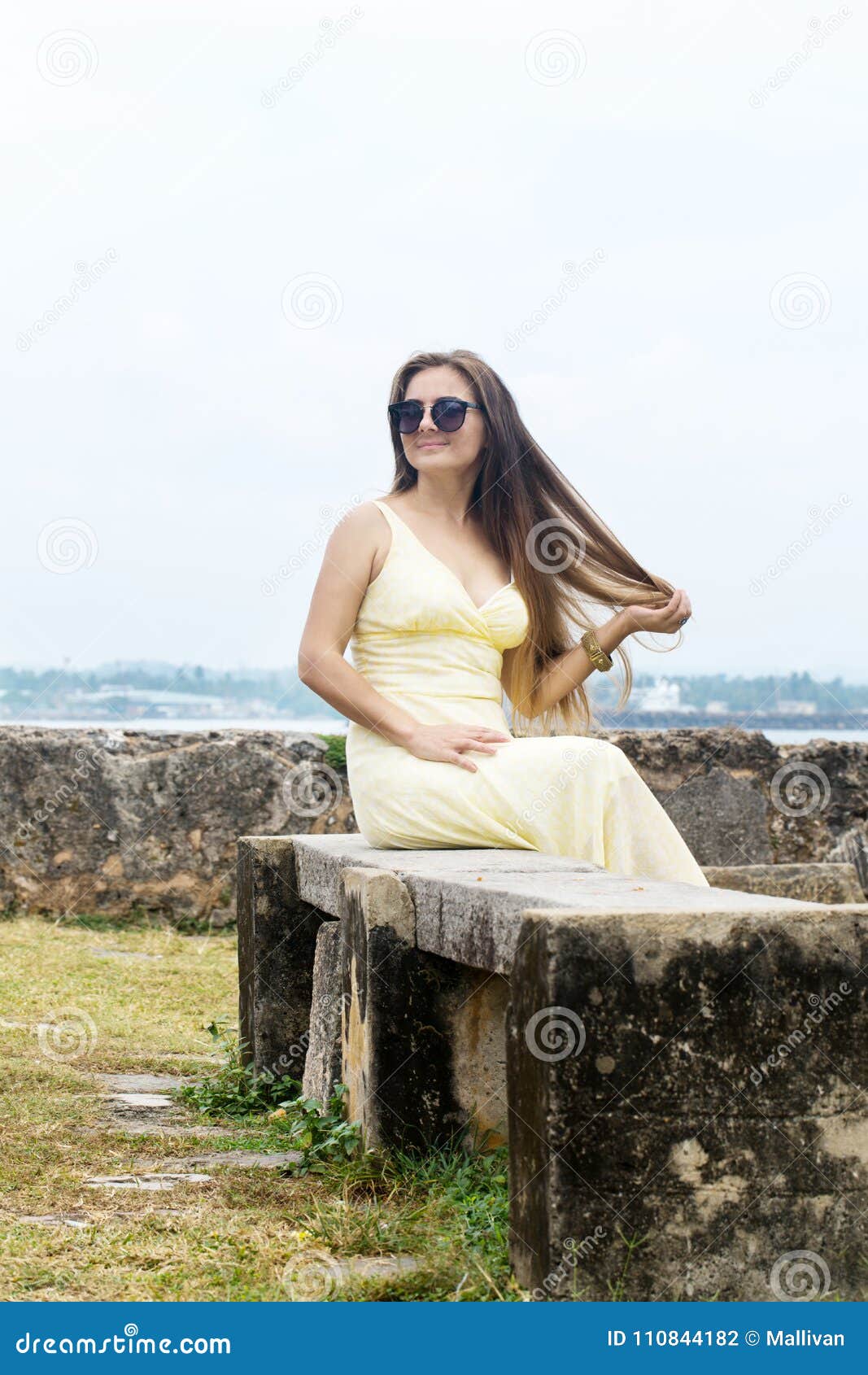 A woman sits on a stone stock photo. Image of casual - 110844182