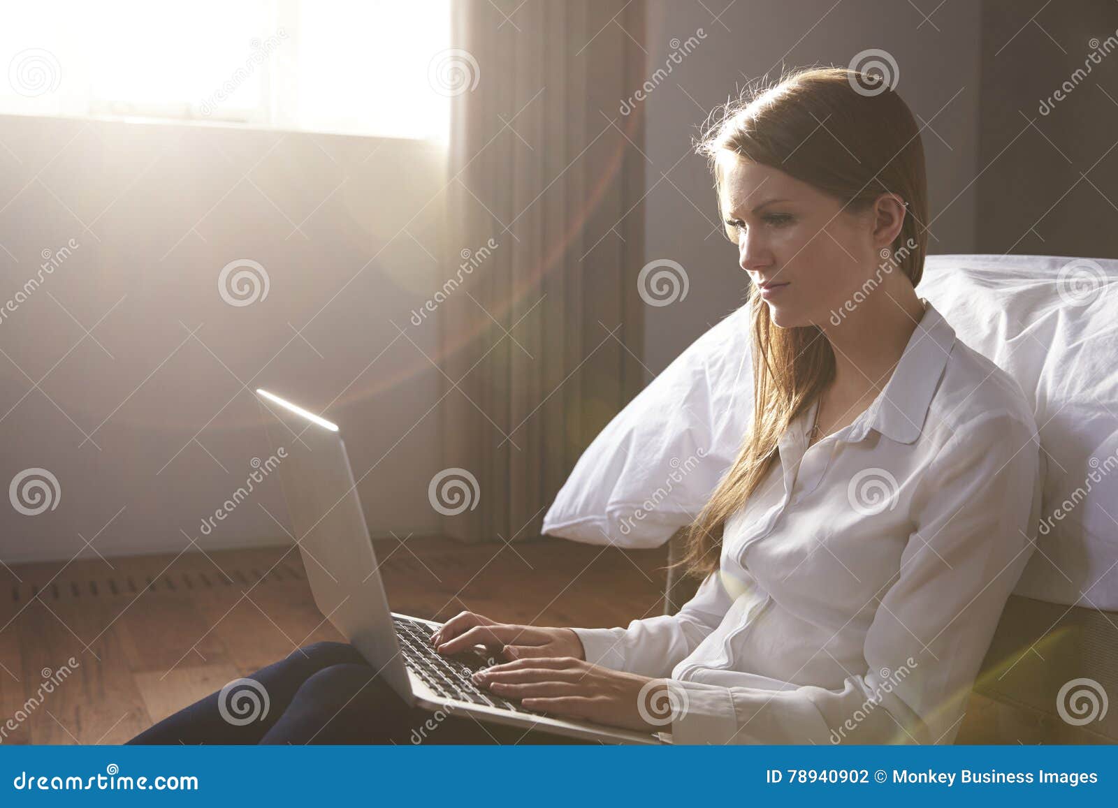Woman Sitting on Bed in Bedroom Using Laptop Computer Stock Photo ...