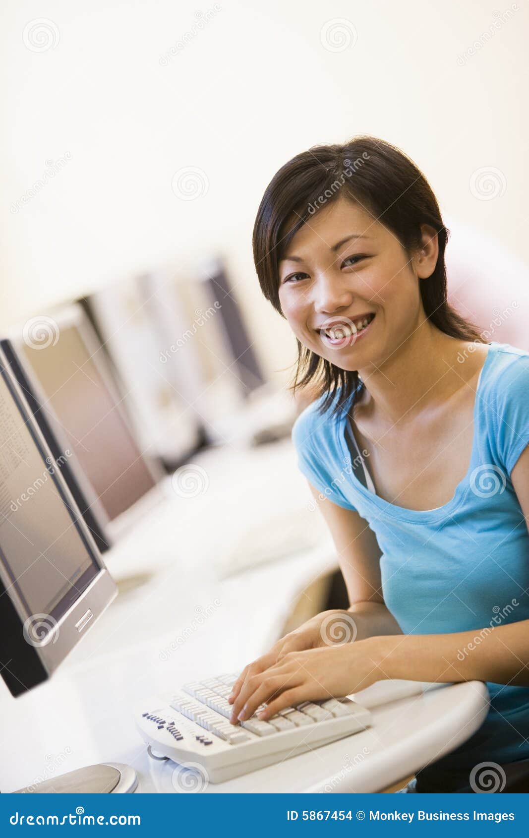 Woman Sitting in Computer Room Typing and Smiling Stock Photo - Image ...