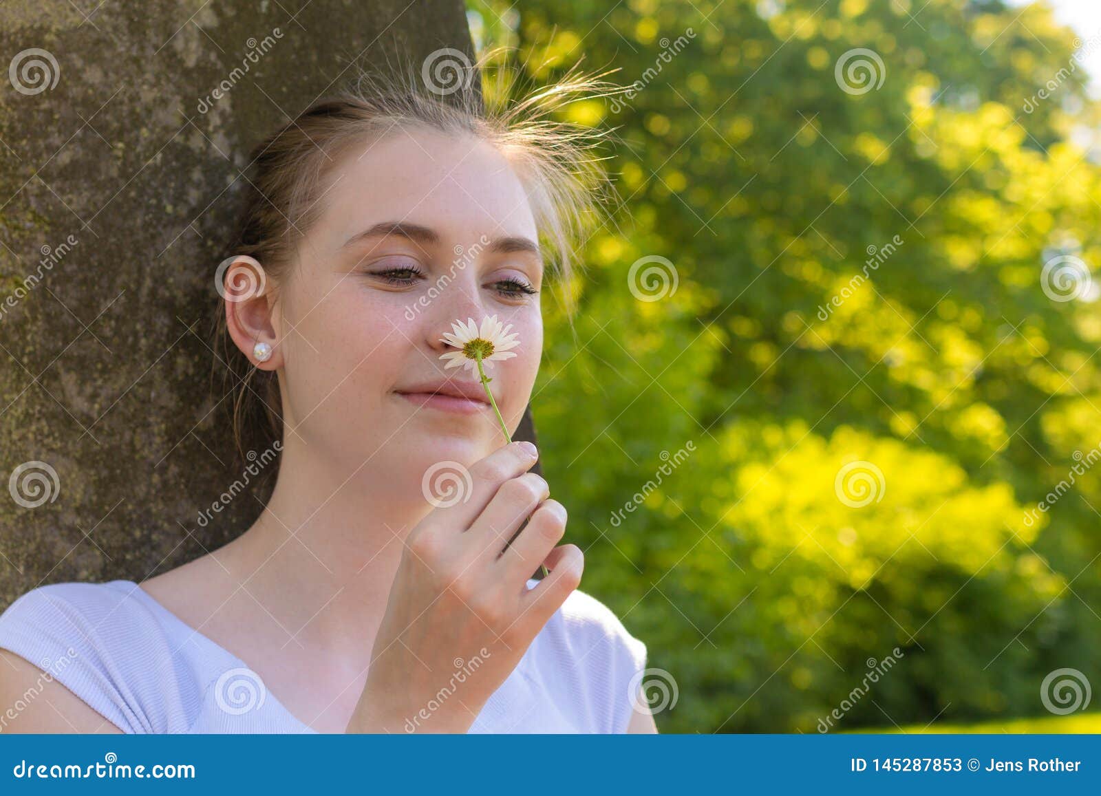 A Woman is Sitting Under a Tree and Smells on a Flower Stock Image ...