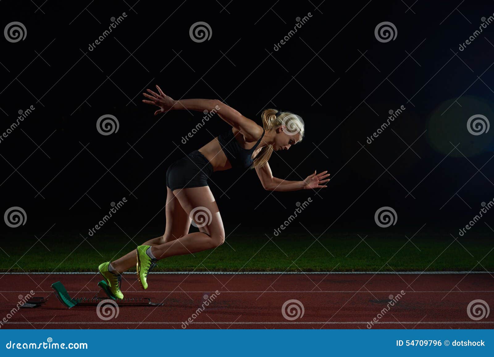 Woman Sprinter Leaving Starting Blocks Stock Photo - Image of field ...