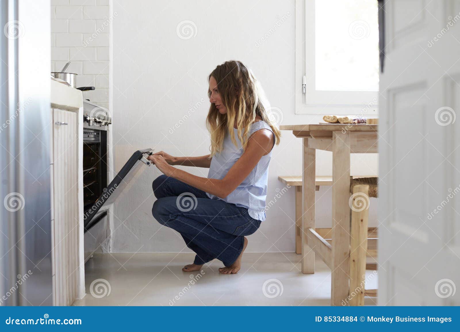 Woman Squatting Down in Kitchen To Look into the Oven Stock Photo ...