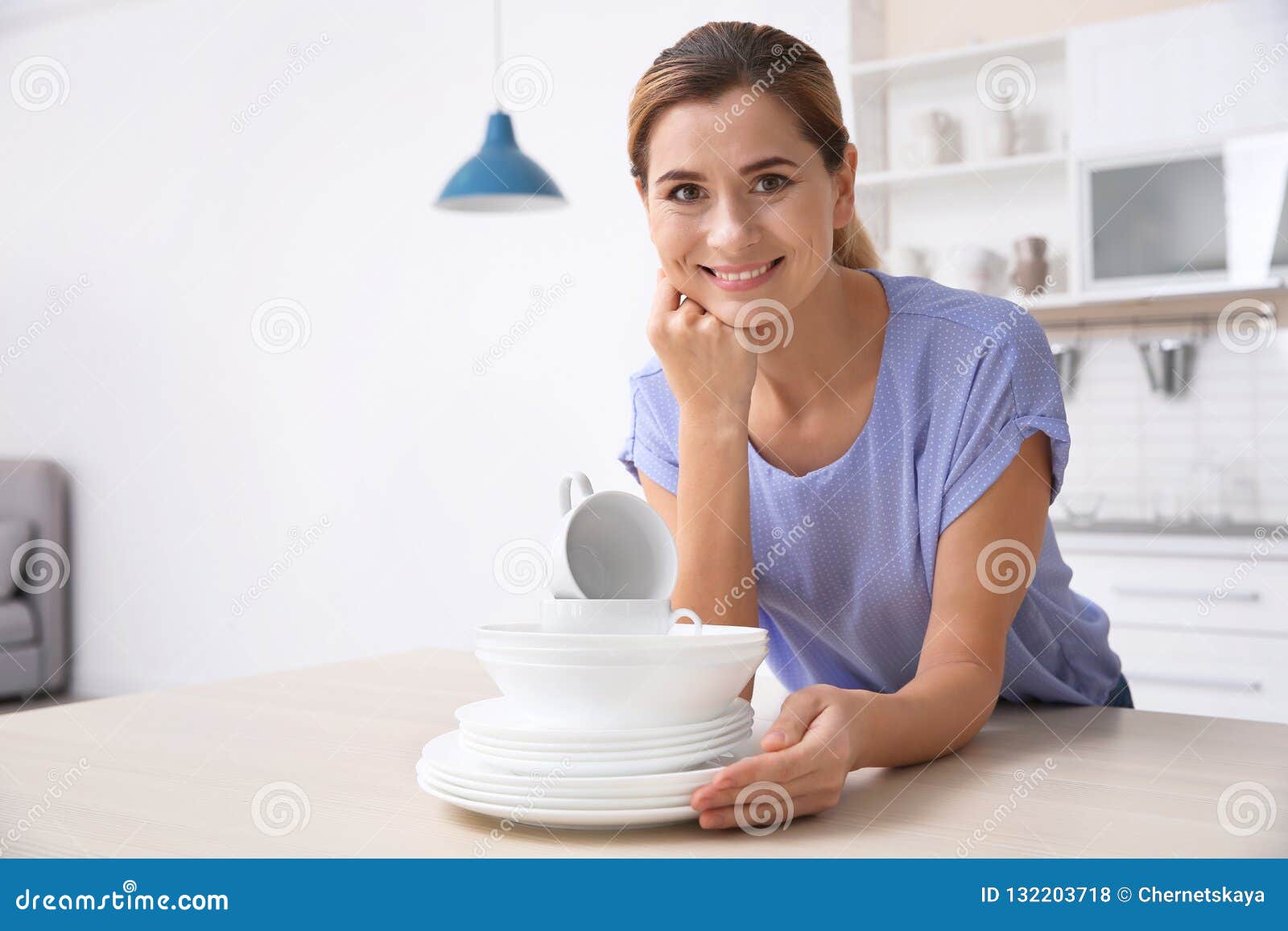 Woman with Stack of Clean Dishes at Kitchen Table. Stock Photo - Image ...