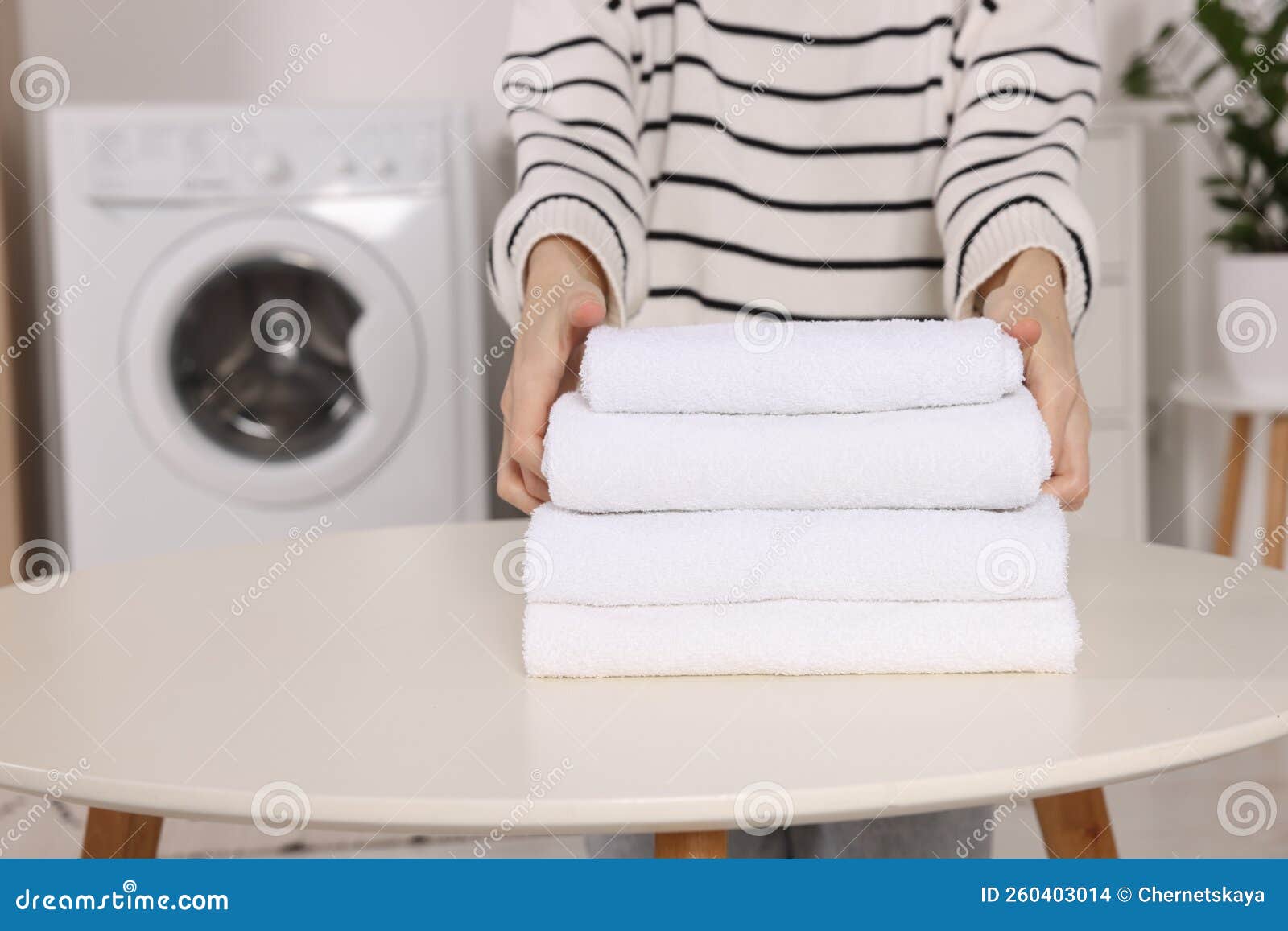 Woman with Stack of Folded Towels at White Table in Laundry Room ...