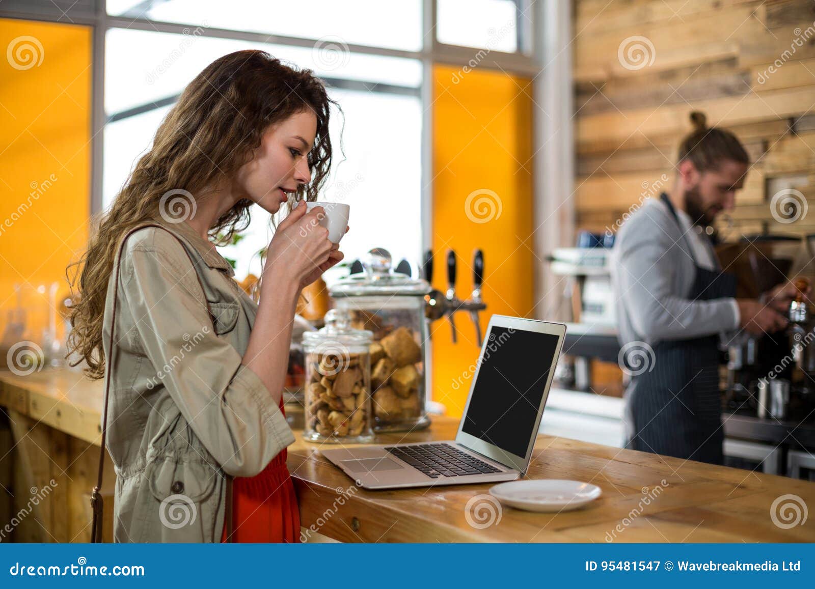 Woman Standing at Counter and Using Laptop while Having Coffee Stock ...