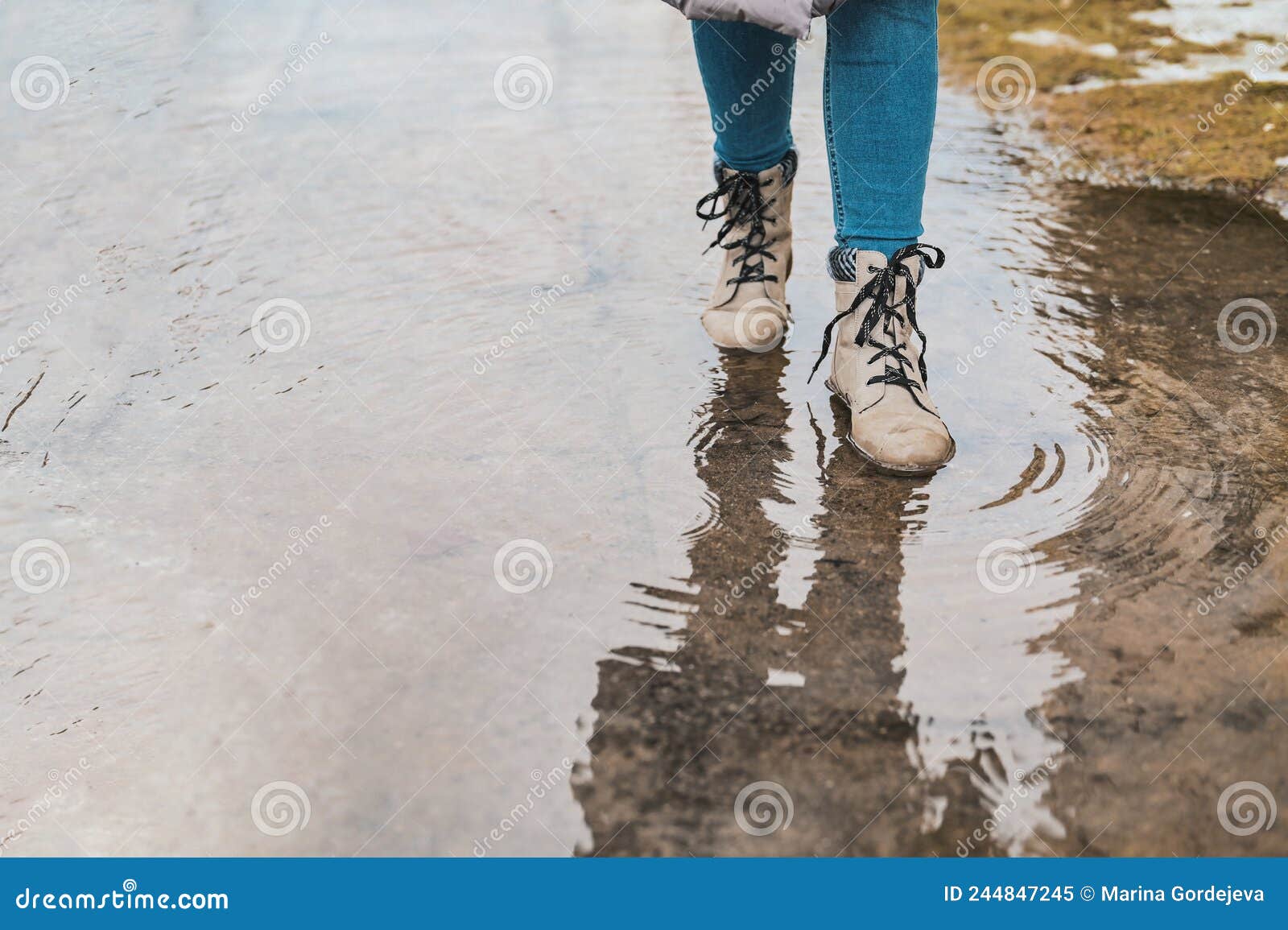 A Woman Steps into a Puddle. Splashes of Water Scatter from Under the ...