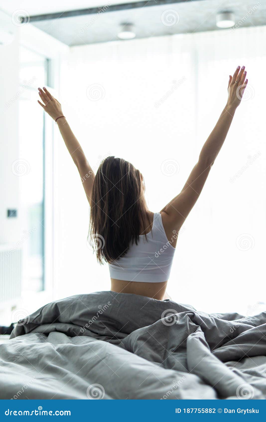 Young Woman Stretching in Bed after Wake Up. Back View Stock Photo ...