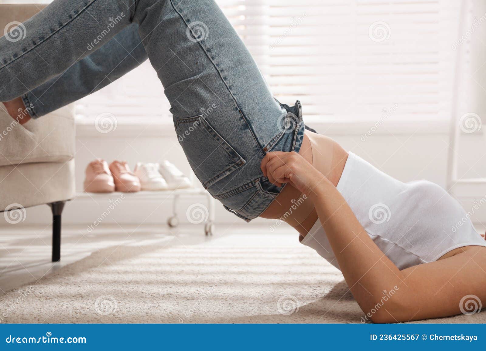Woman Struggling To Squeeze Into Tight Jeans While Lying On Floor At Home Closeup Stock Image