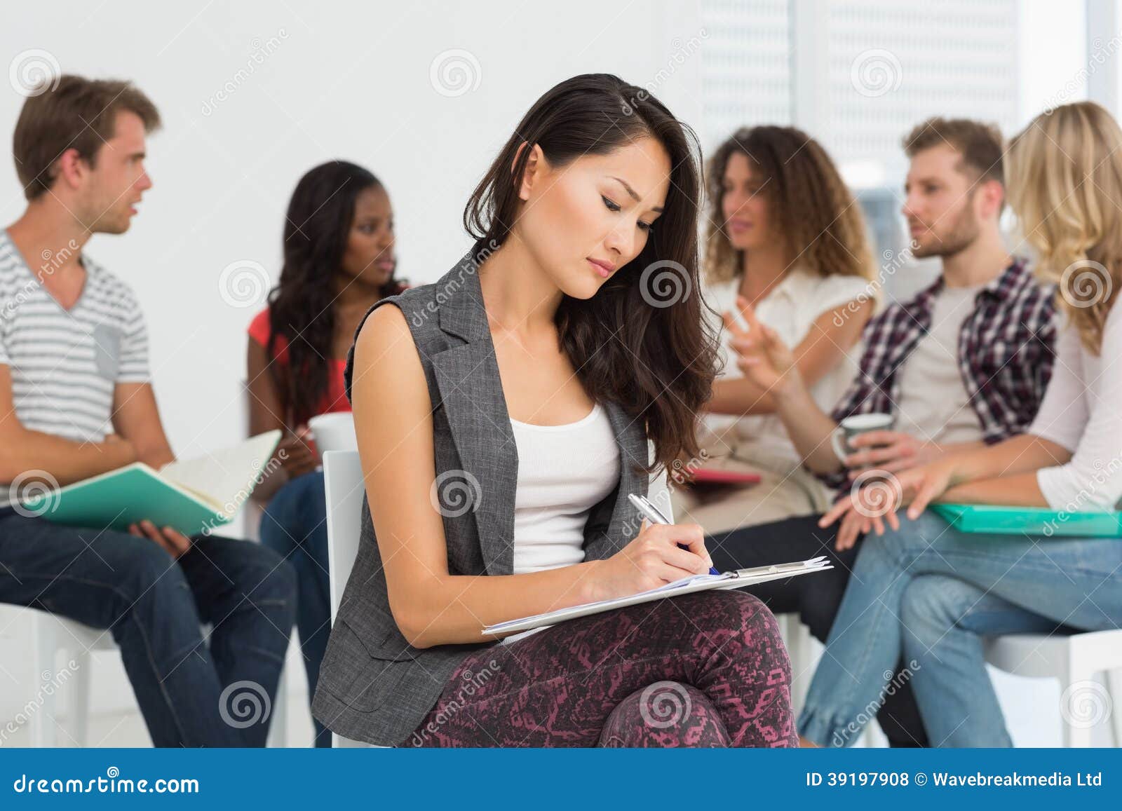 Woman Taking Notes while Colleagues are Talking Behind Her Stock Photo ...