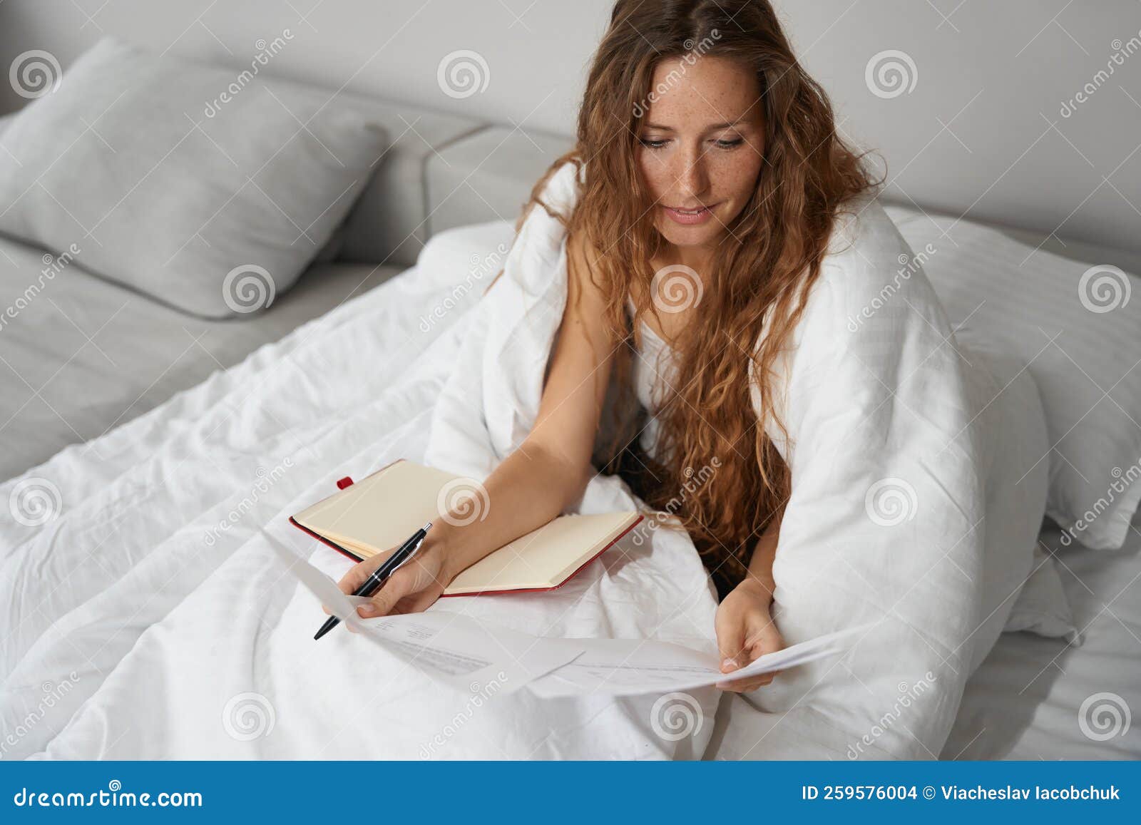 Woman Taking Notes in Notebook in Bed Covered with Blanket Stock Photo ...