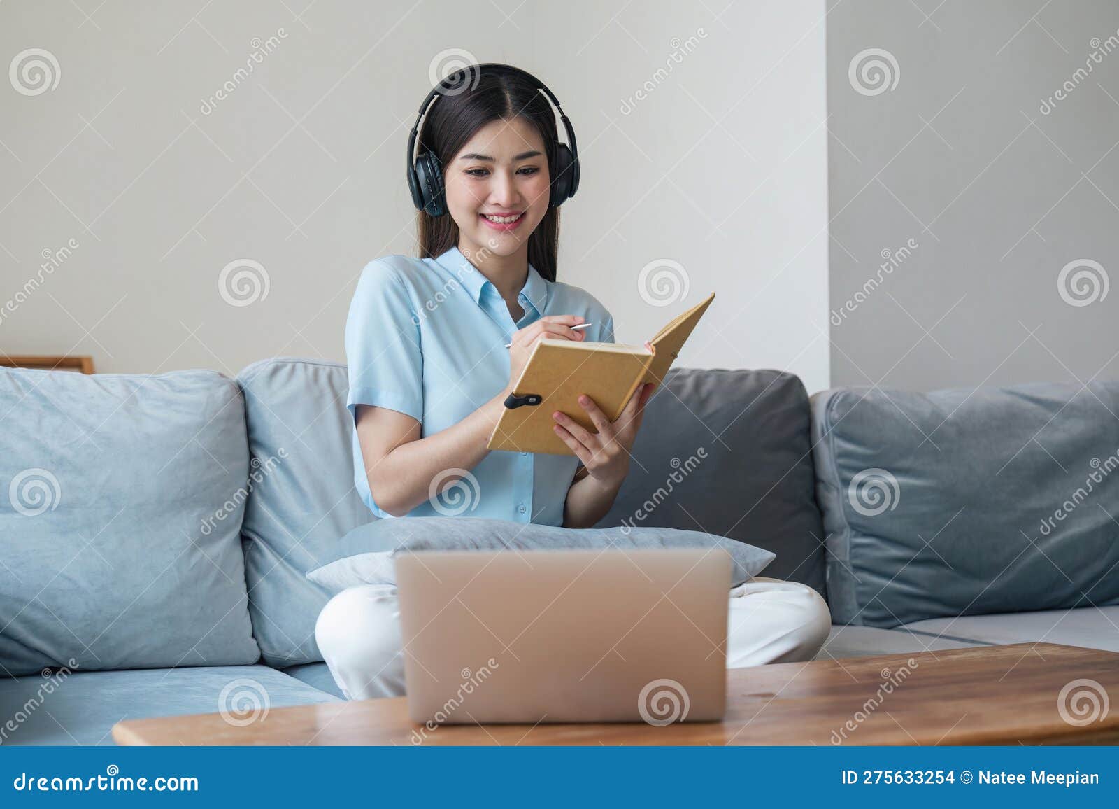 Woman Taking Notes in Notebook while Using Laptop at Home in Living ...