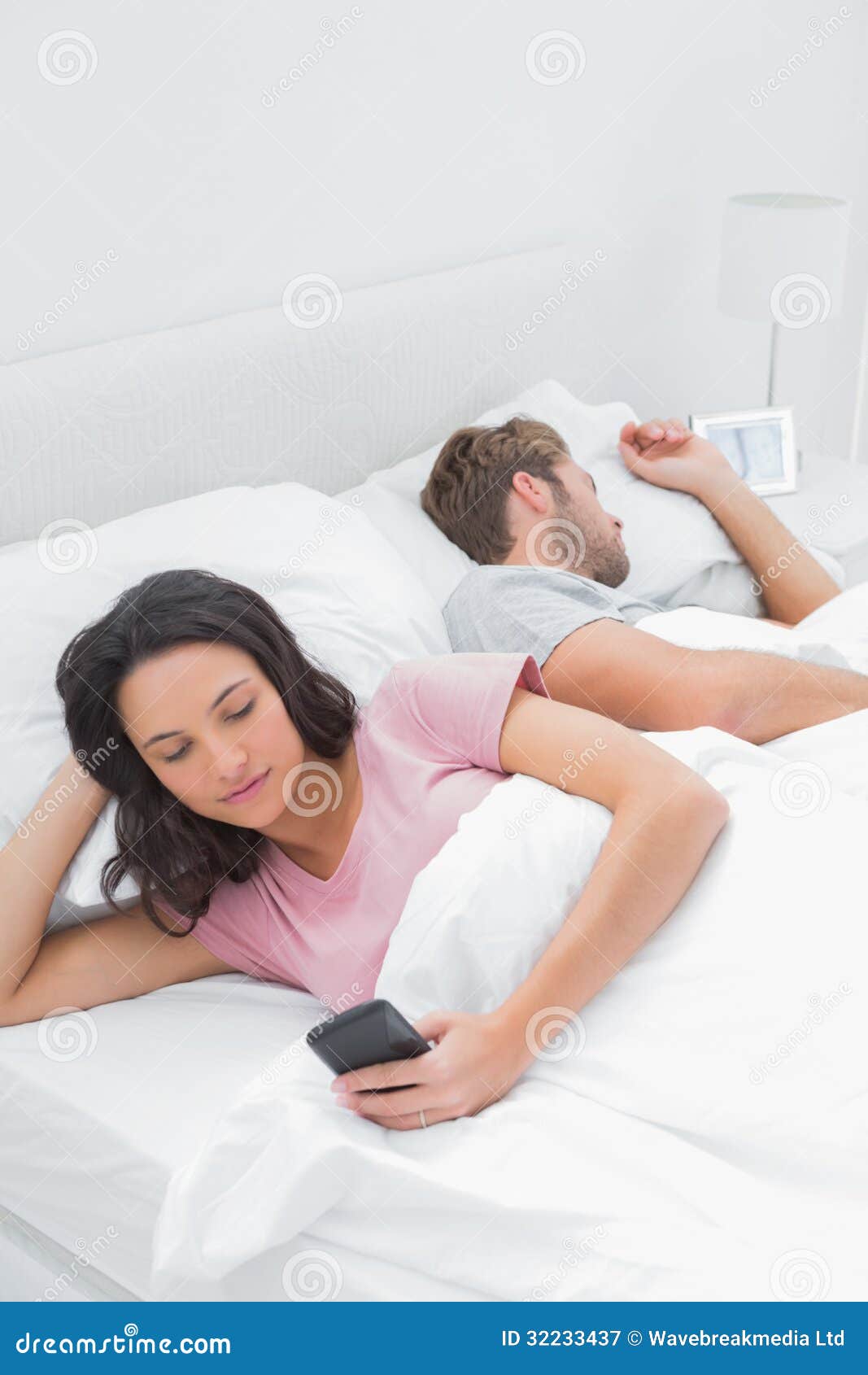 Woman Text Messaging in Bed while Her Husband is Sleeping Stock Image ...