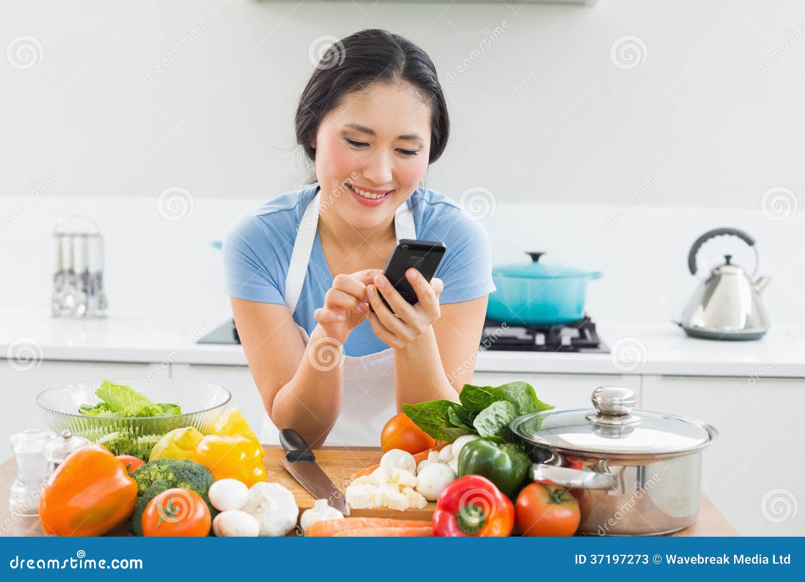 Woman Text Messaging in Front of Vegetables in Kitchen Stock Image ...