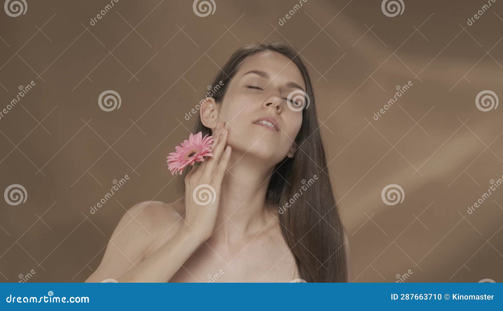 A Woman Touches Her Hand With A Pink Gerbera Flower To The Skin Of Her