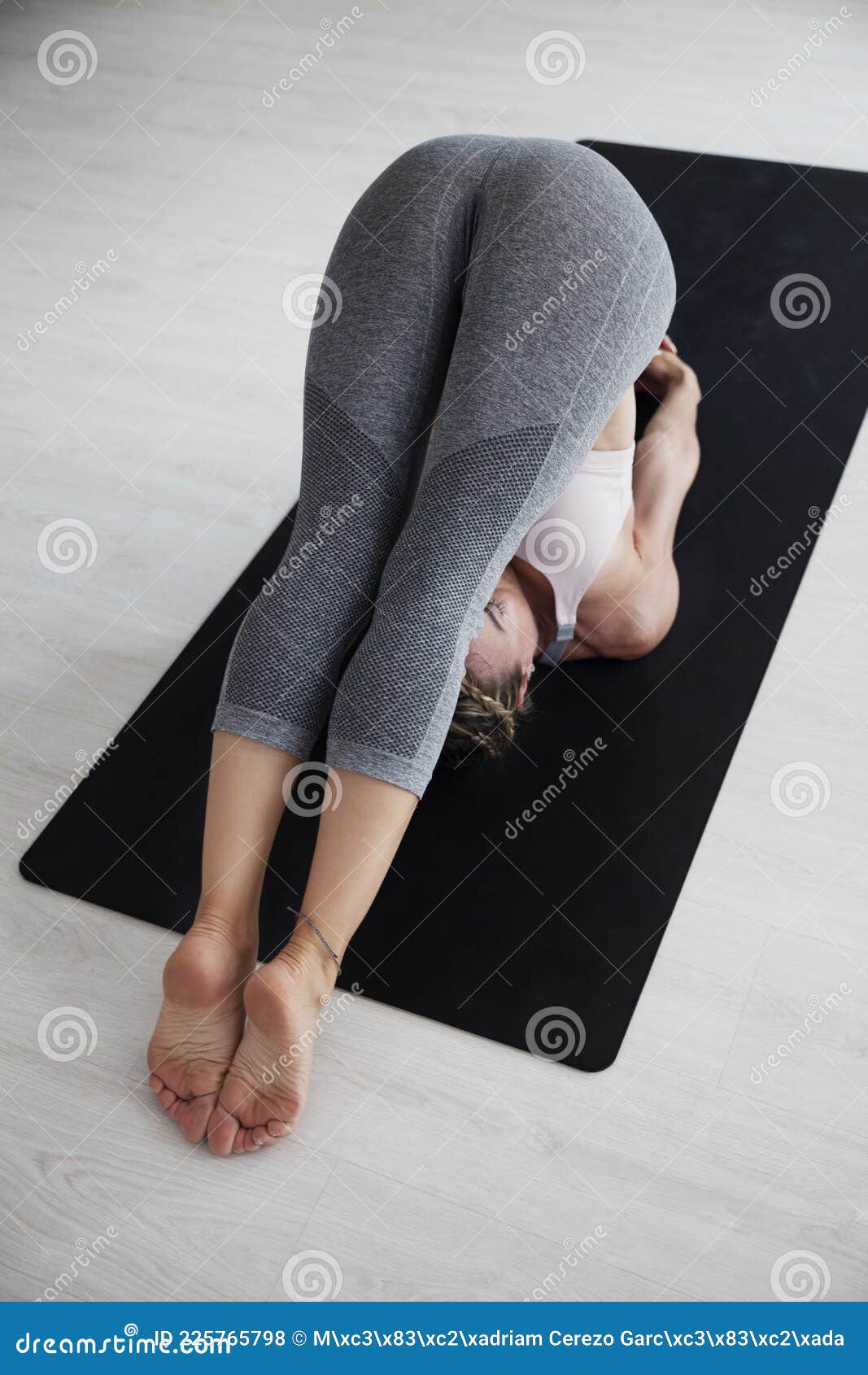 A Woman is Training in an Inverted Exercise, she is Doing Halasana Pose ...
