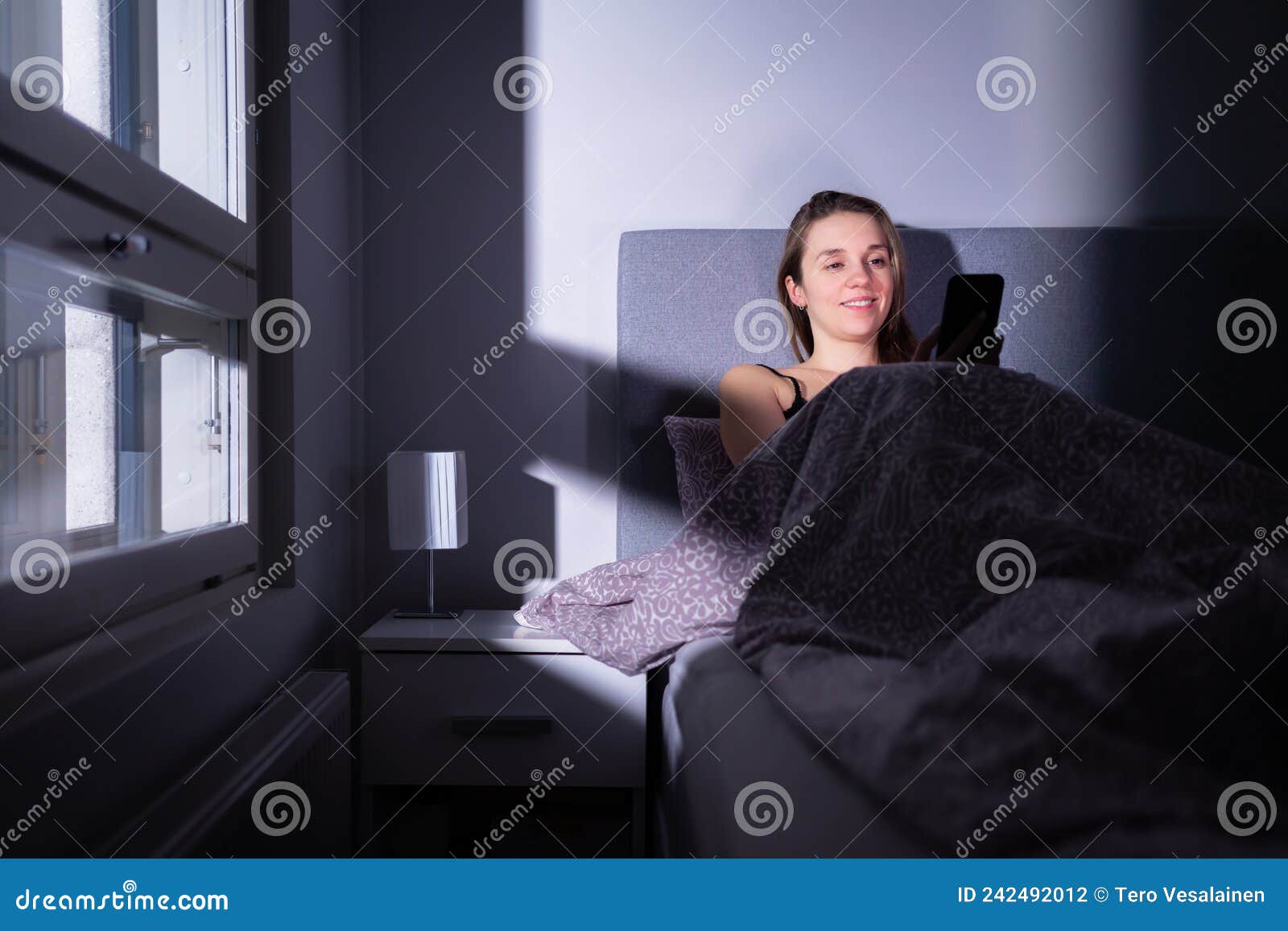 Woman Using Cell Phone in Bed Smiling Happy. Working Late or Texting ...