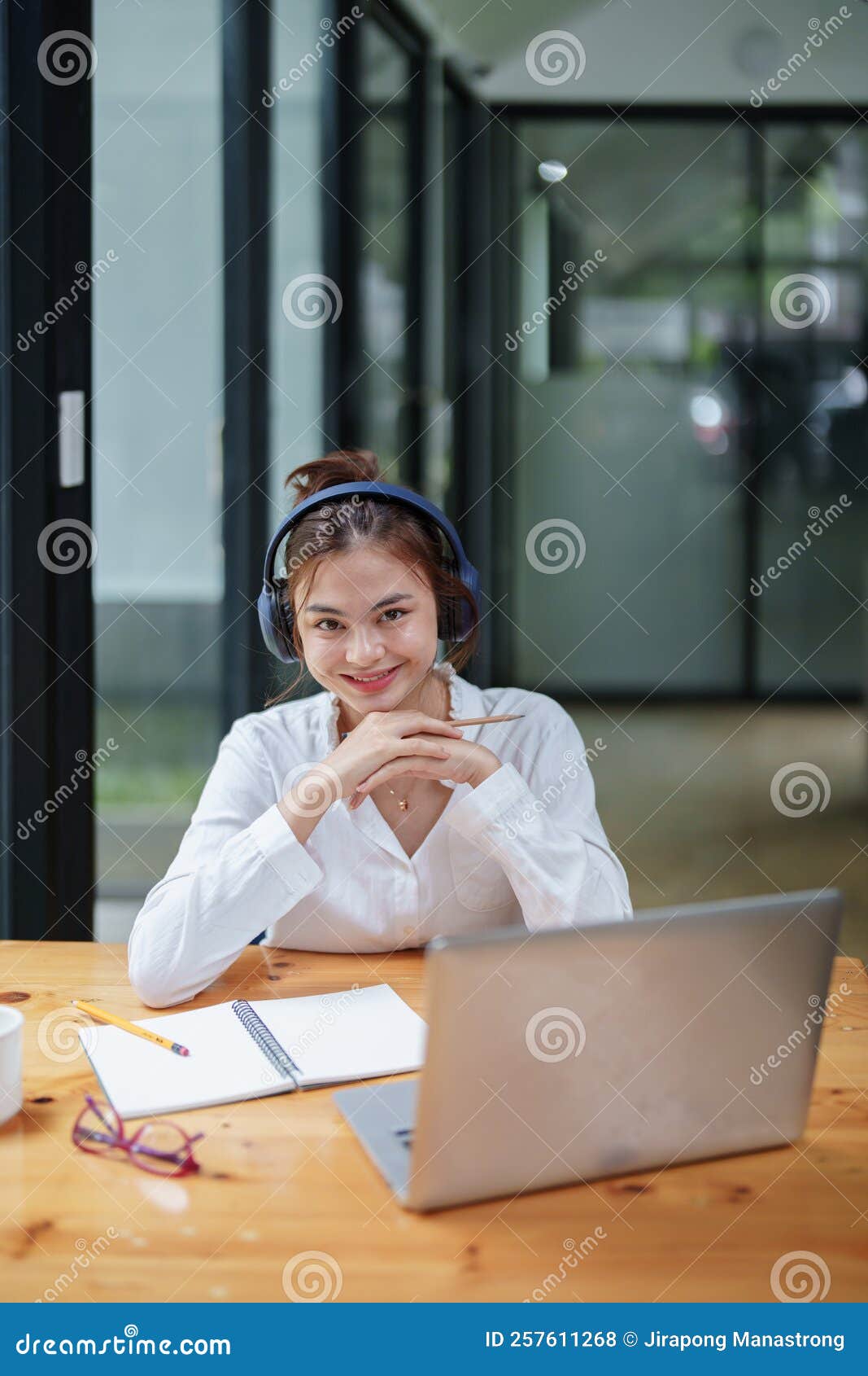 Woman Using Computer, Earphone and Notebook during a Video Conference ...