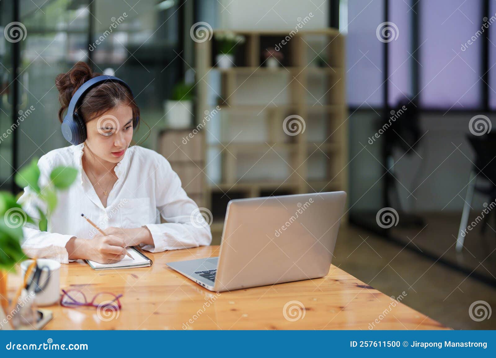 Woman Using Computer, Earphone and Notebook during a Video Conference ...