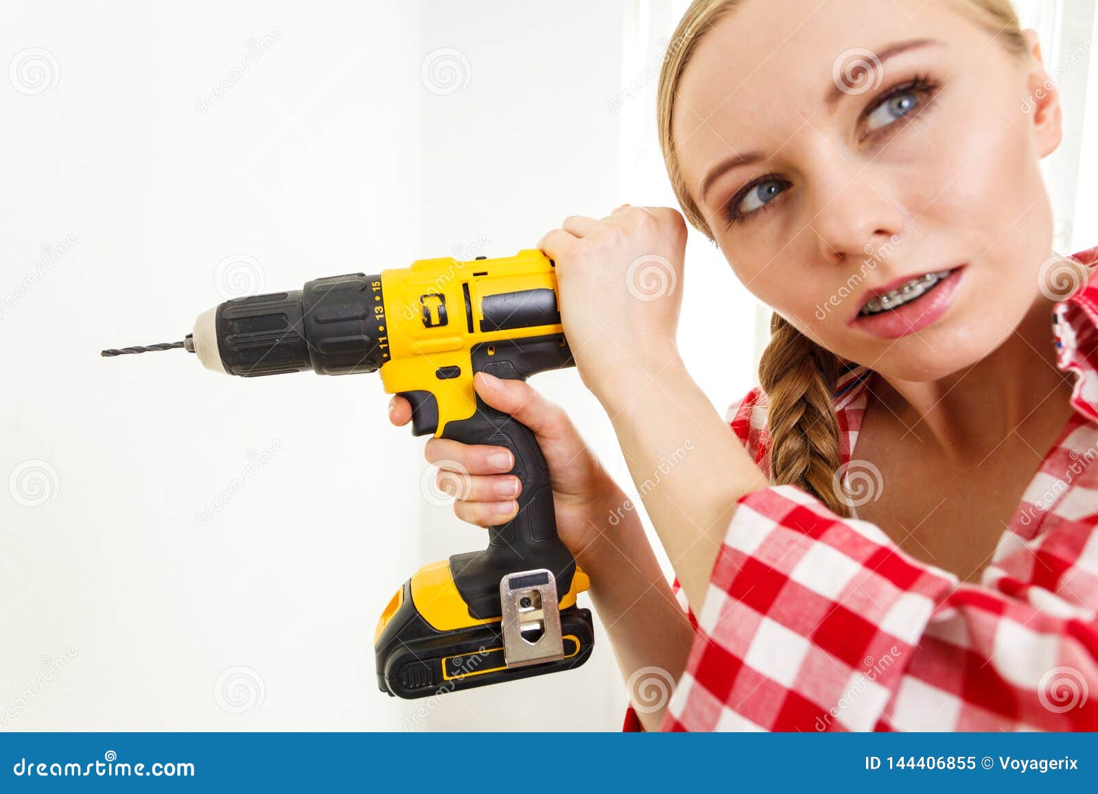 Woman using drill on wall stock image. Image of builder - 144406855