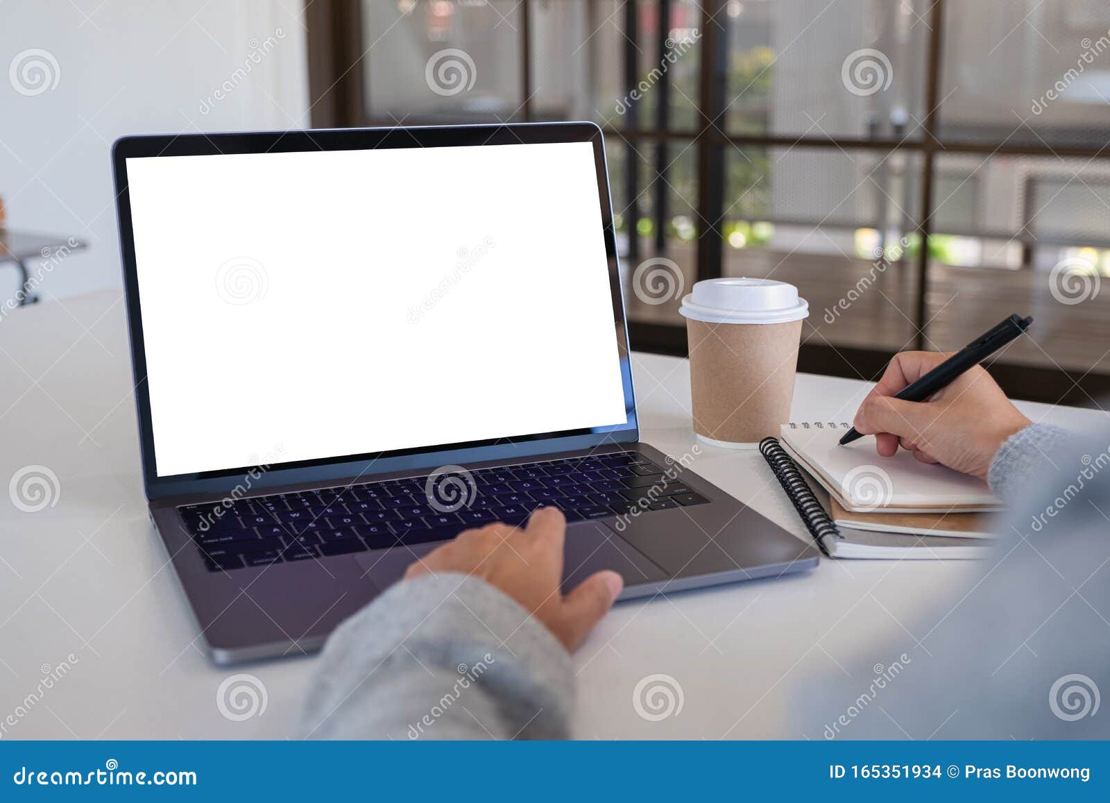 A Woman Using Laptop with Blank White Desktop Screen while Writing on a ...