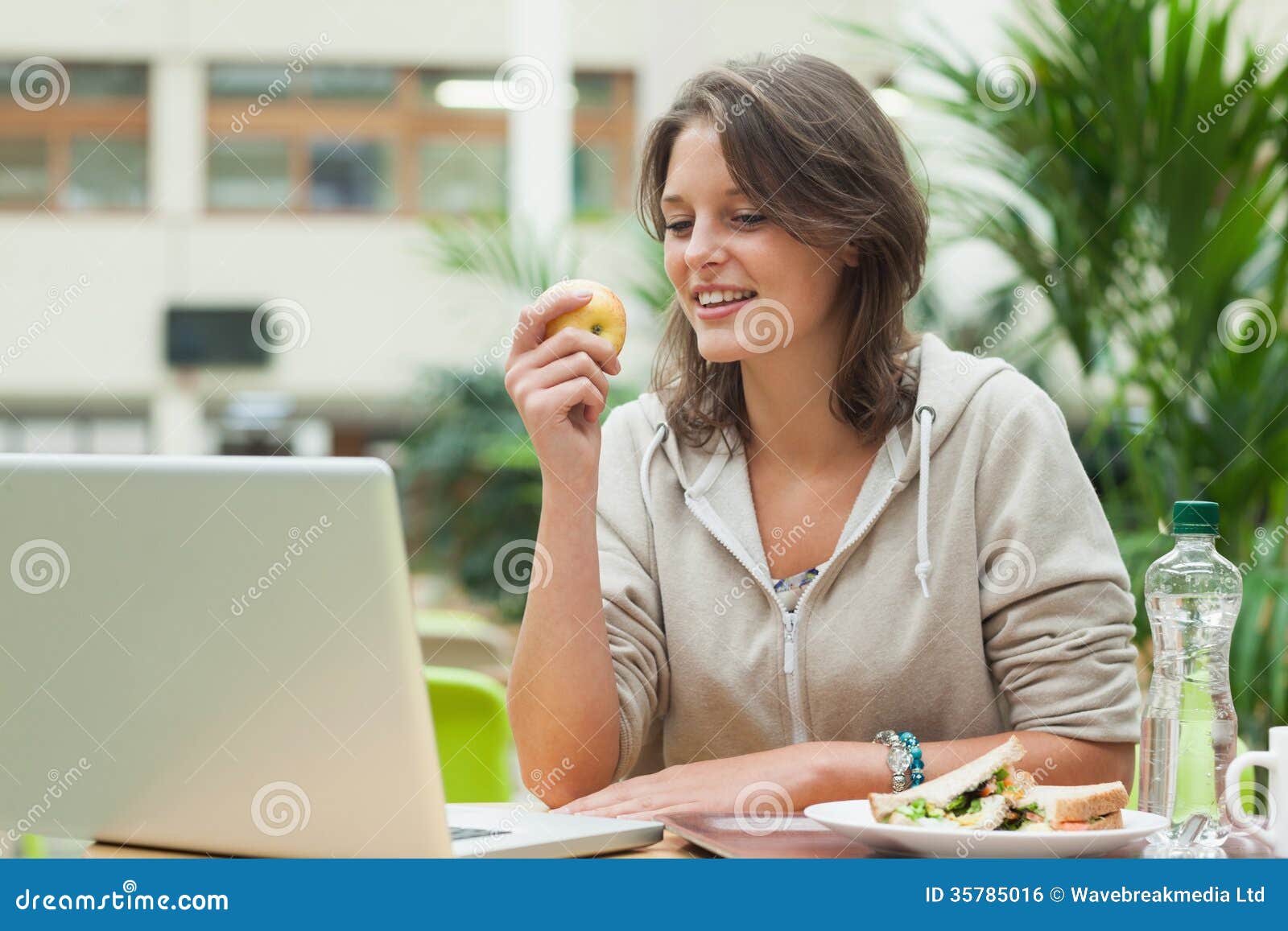Woman Using Laptop while Eating Apple Stock Photo - Image of smile ...