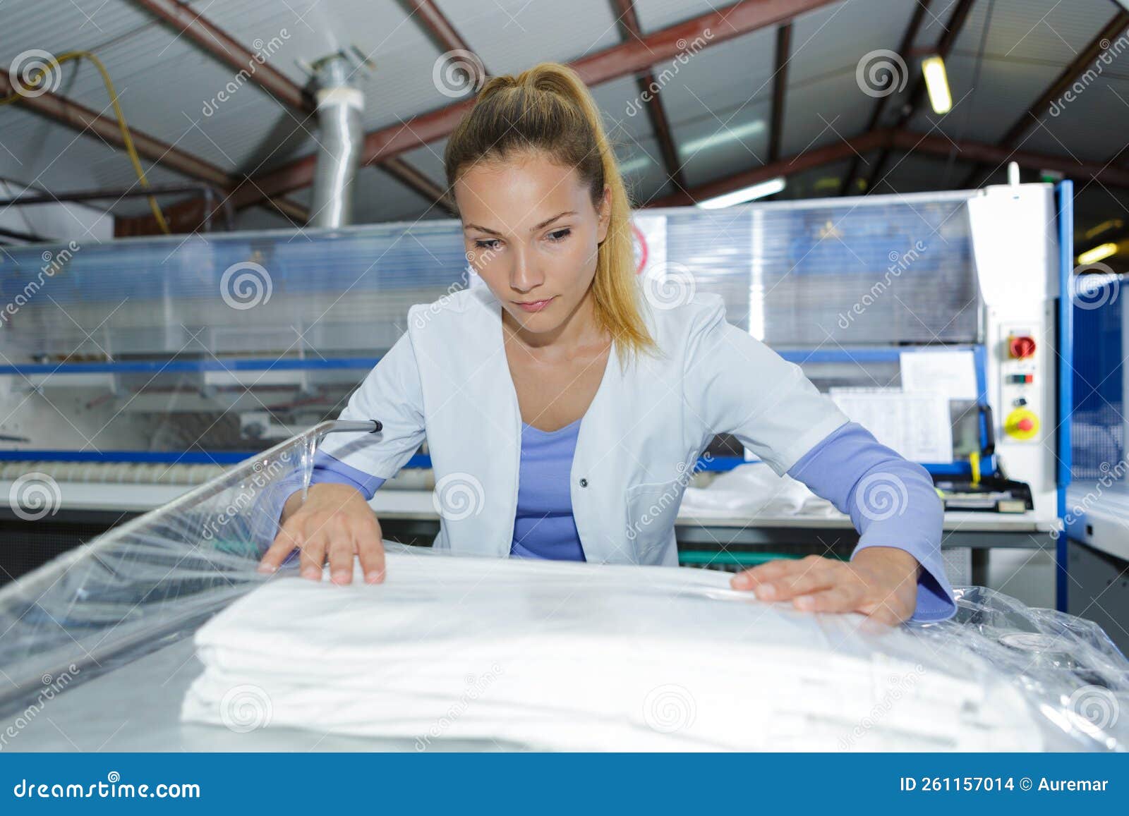 Woman Using Machine To Wrap Clean Laundry in Plastic Stock Photo ...
