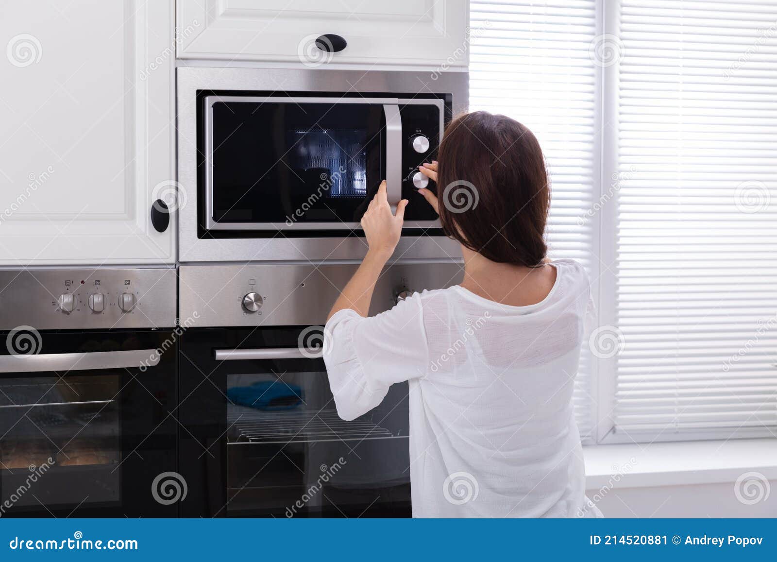 Woman Using Microwave Oven stock image. Image of adult - 214520881