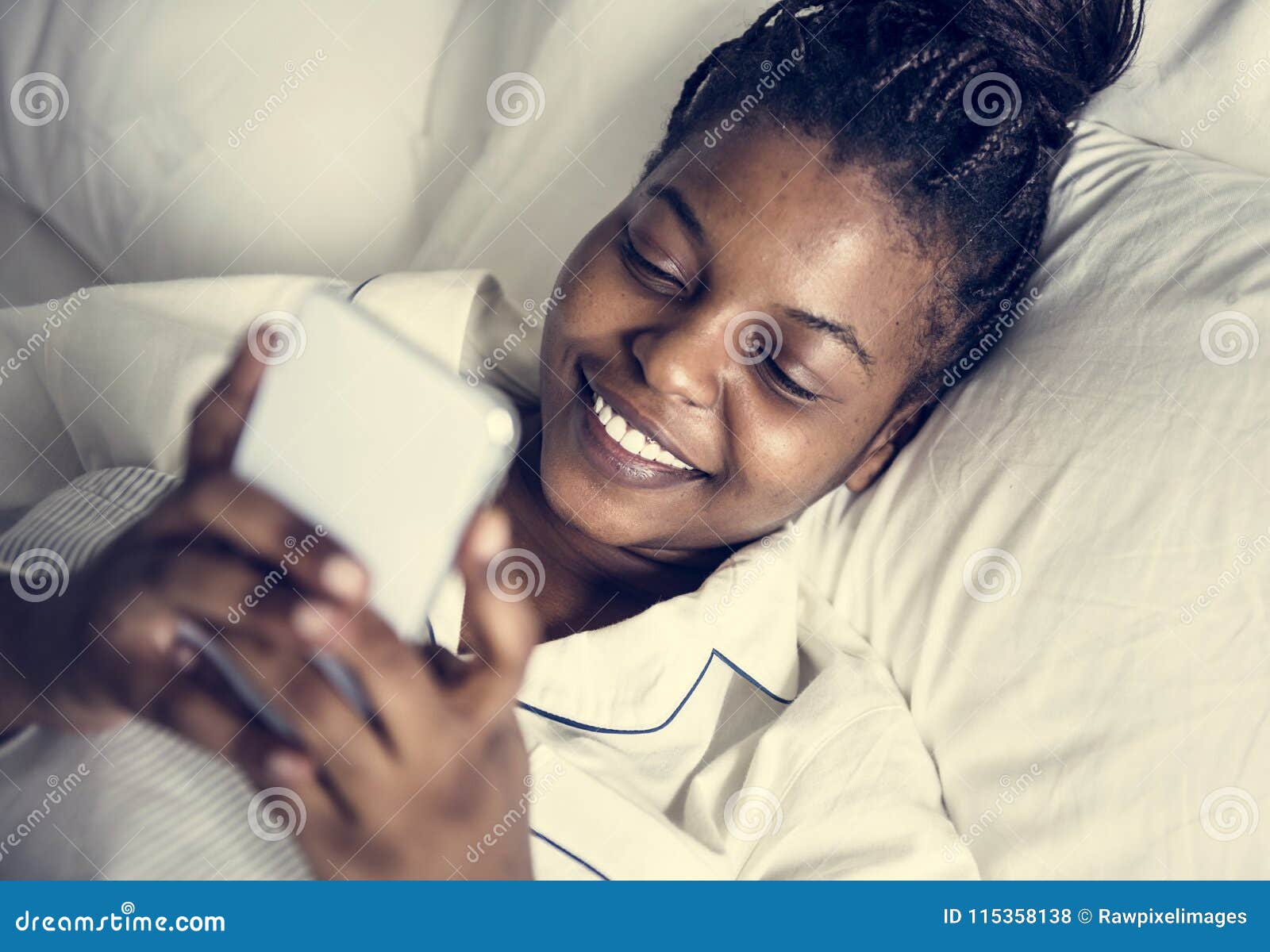 A Woman Using a Phone in Bed Stock Photo - Image of africa, bedding ...