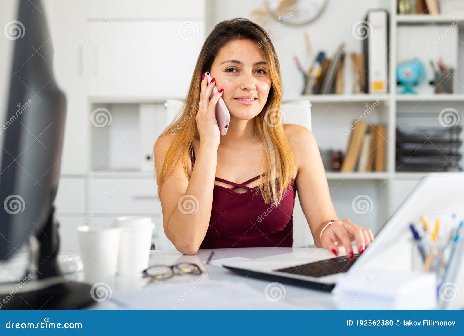 Woman Using Phone and Working with Laptop in Office Stock Photo - Image ...