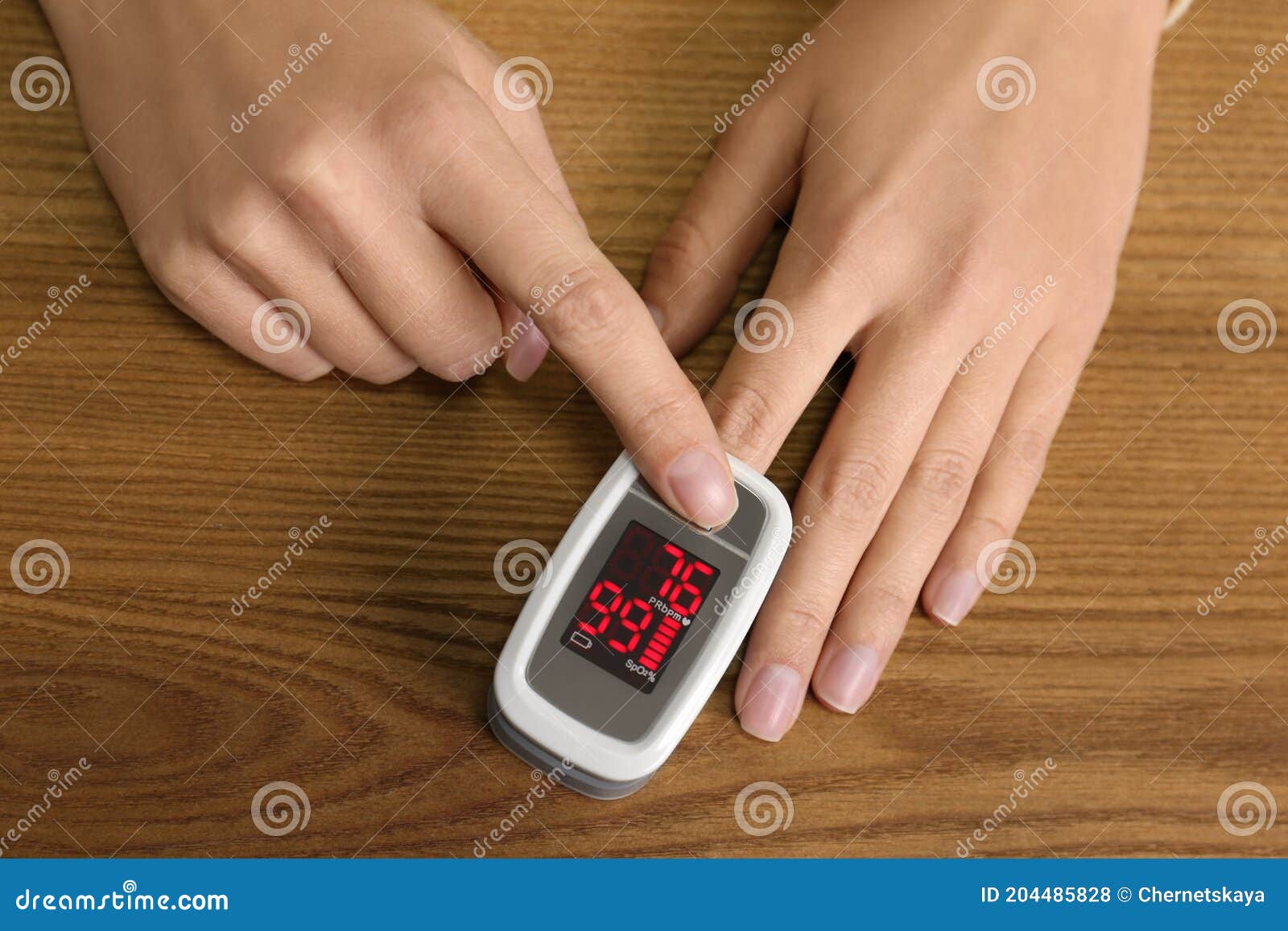 Woman Using Pulse Oximeter for Oxygen Level Testing at Wooden Table ...