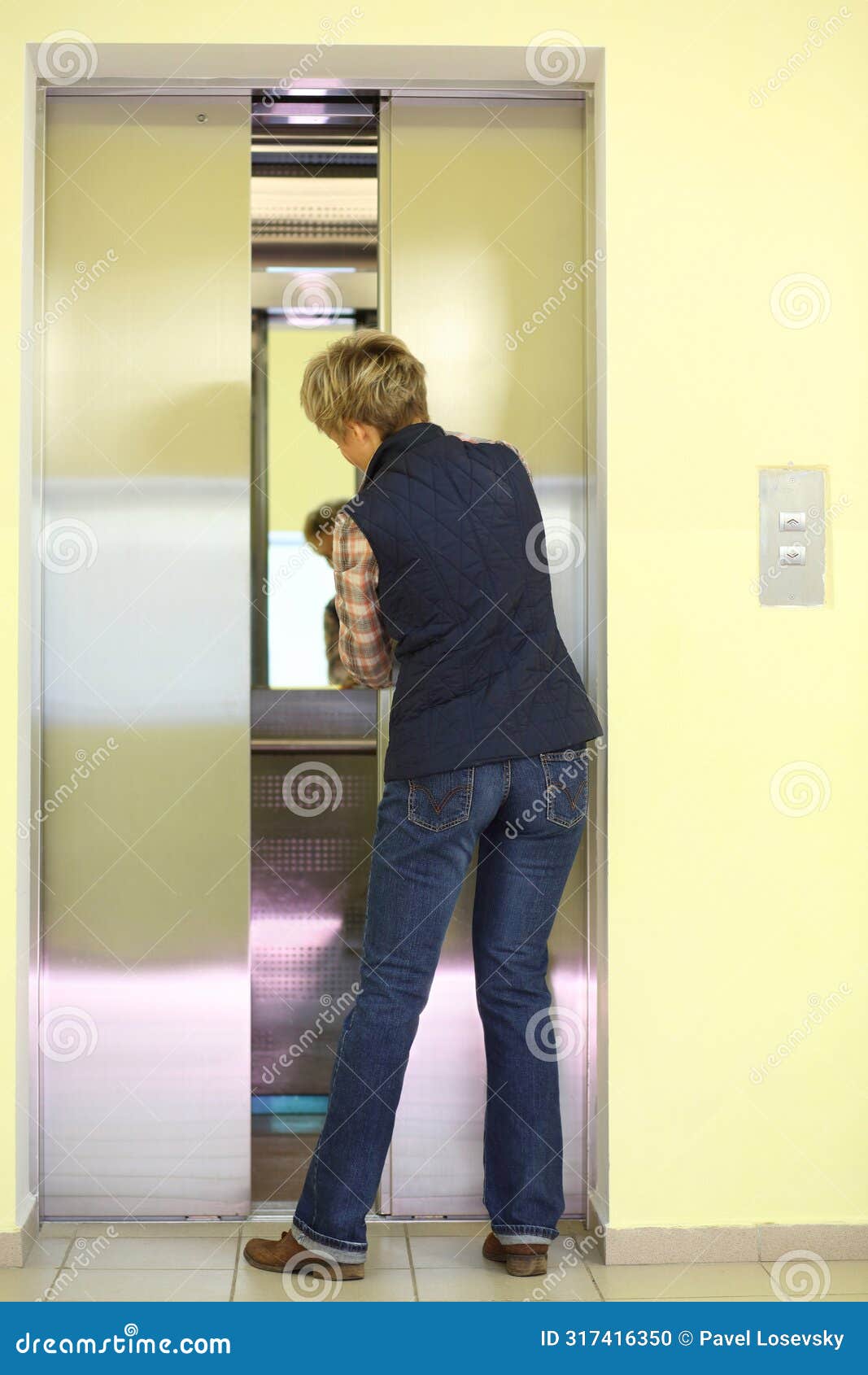 A Woman in a Vest and Jeans Pushing Elevator Stock Photo - Image of ...