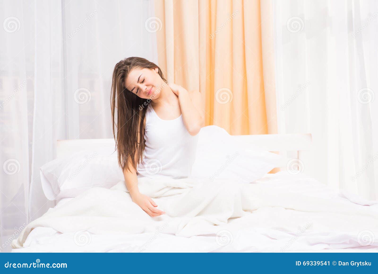 Woman Waking Up And Yawning With A Stretch While Sitting In Bed Stock