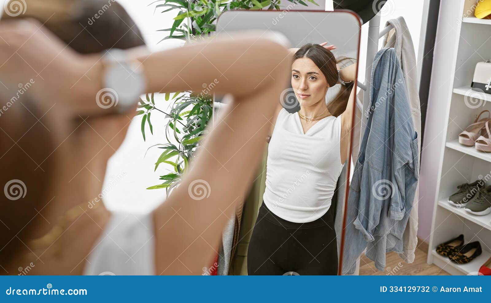 A Woman in a Wardrobe Room Trying on Clothes, Looking at Her Reflection ...