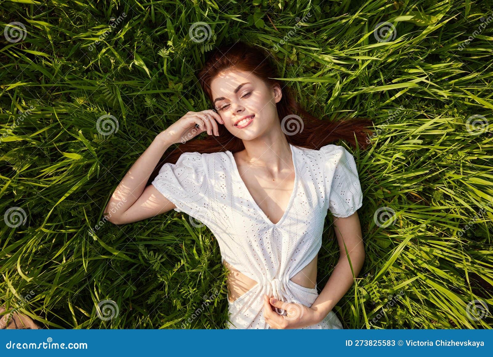 A Woman In A White Dress Is Lying On The Grass In Sunset Stock Image