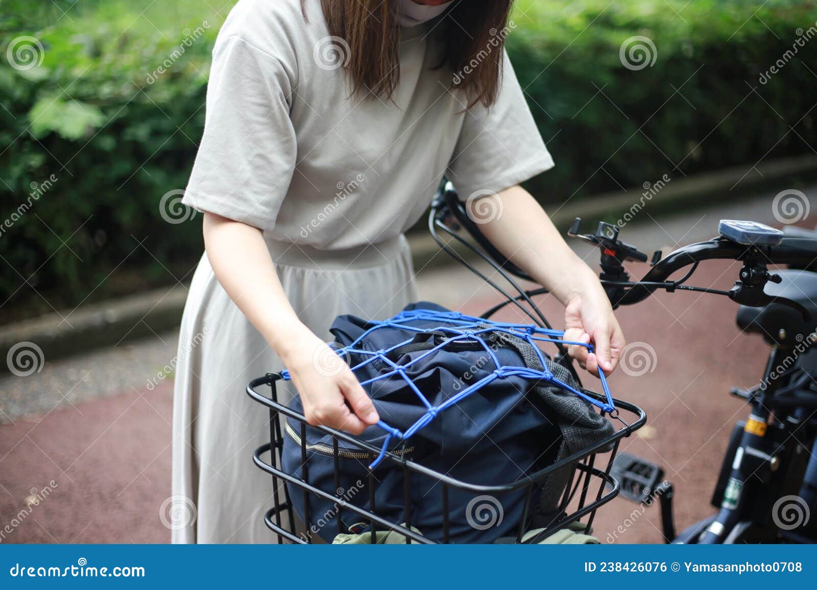 A Woman Who Wears a Bicycle Net in the Front Basket of a Bicycle Stock ...