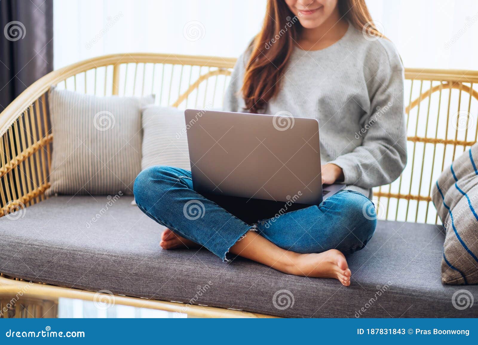 A Woman Working On Laptop Computer While Sitting On A Sofa At Home