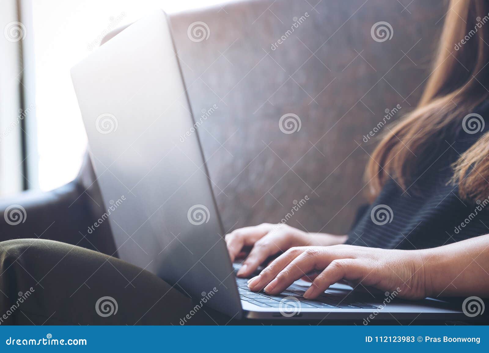 A Woman Working and Typing on Laptop Keyboard while Sitting on Sofa ...