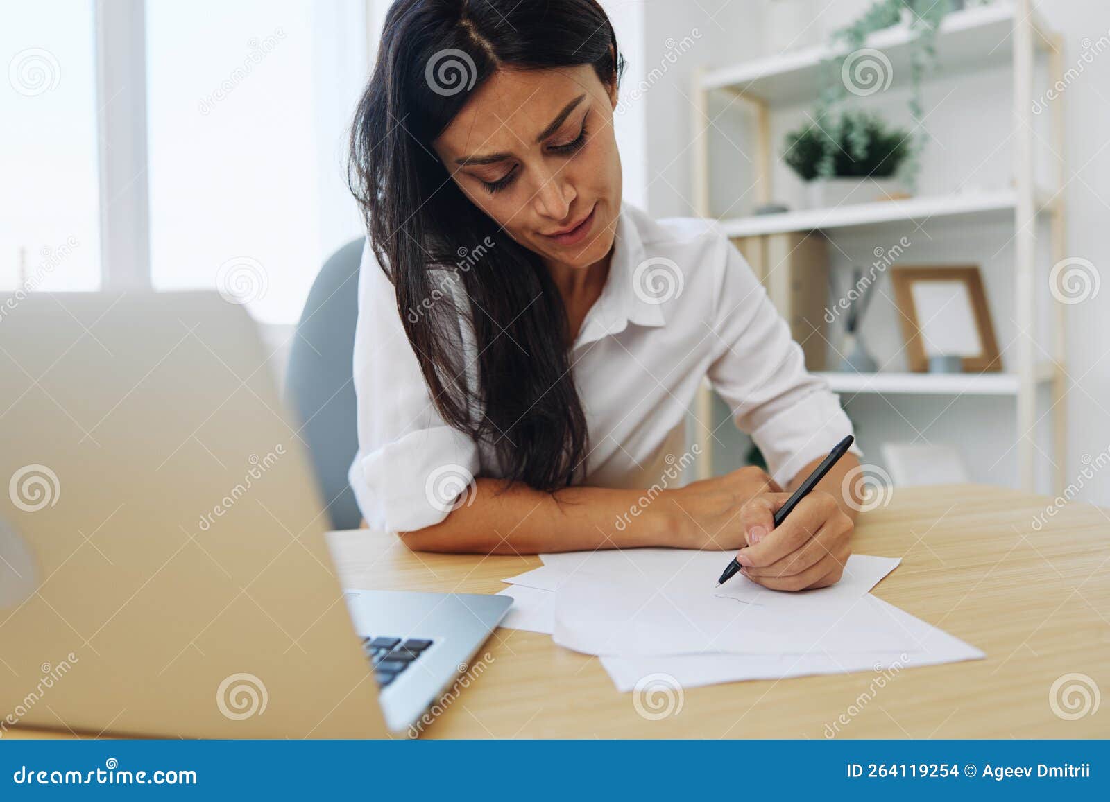 A Woman Works and Learns by Writing Down Text on Paper with a Pen and ...