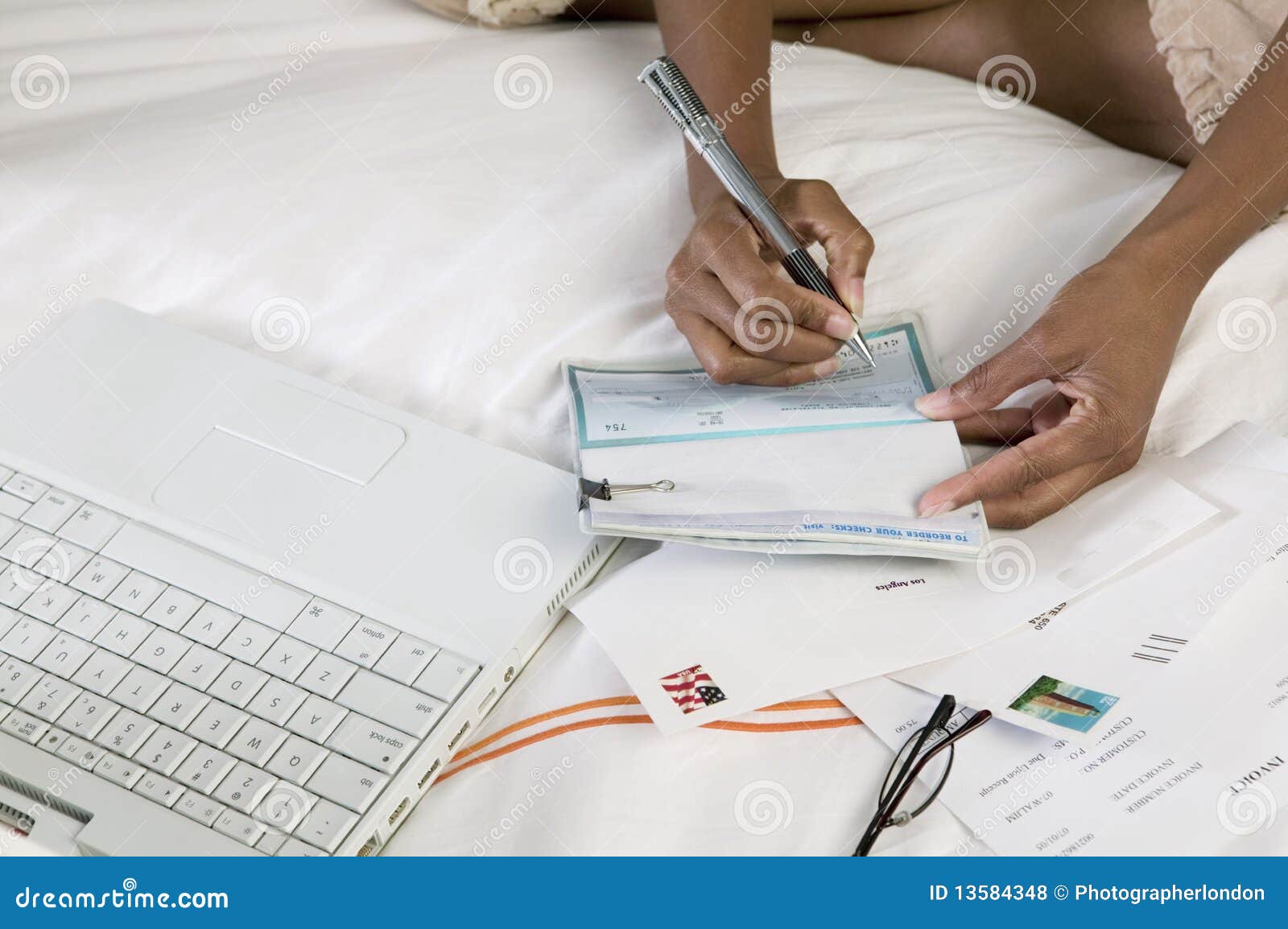 Woman Writing Cheque on Bed by Laptop Stock Photo - Image of writing ...
