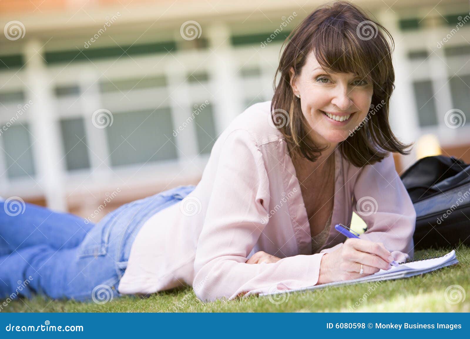 A Woman Writing Notes while Lying on a Campus Lawn Stock Photo - Image ...