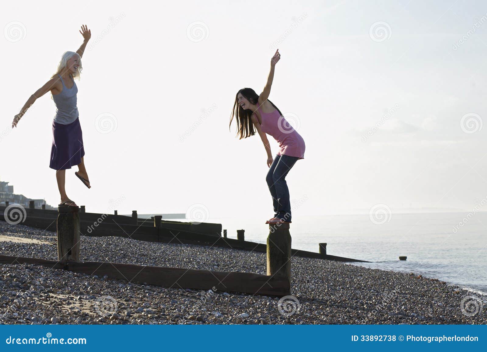 Women Balancing on Wave Breakers at Beach Stock Photo - Image of people ...