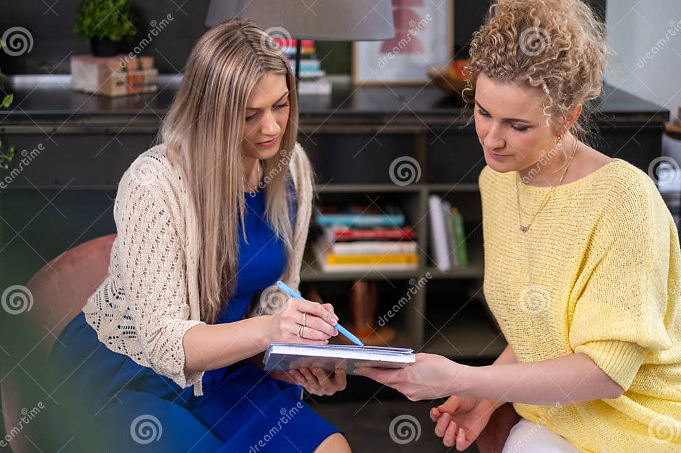 Women Collaborating on Project, Sharing Ideas while Writing on Document ...