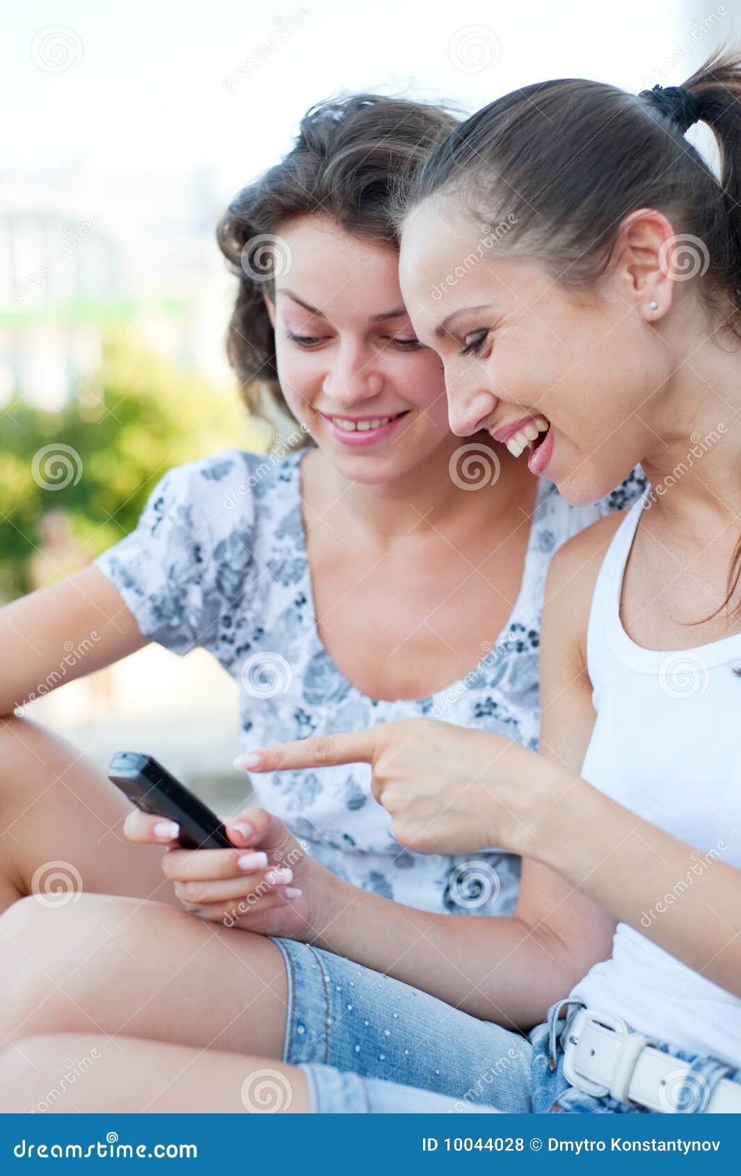 Women Laughing and Looking at Cellphone Stock Photo - Image of friends ...